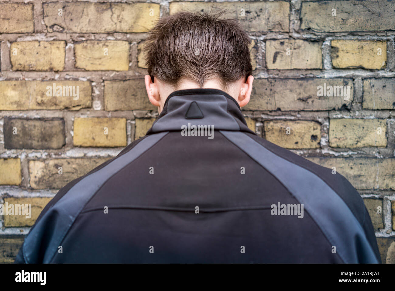 Boy standing behind wall hi-res stock photography and images - Alamy