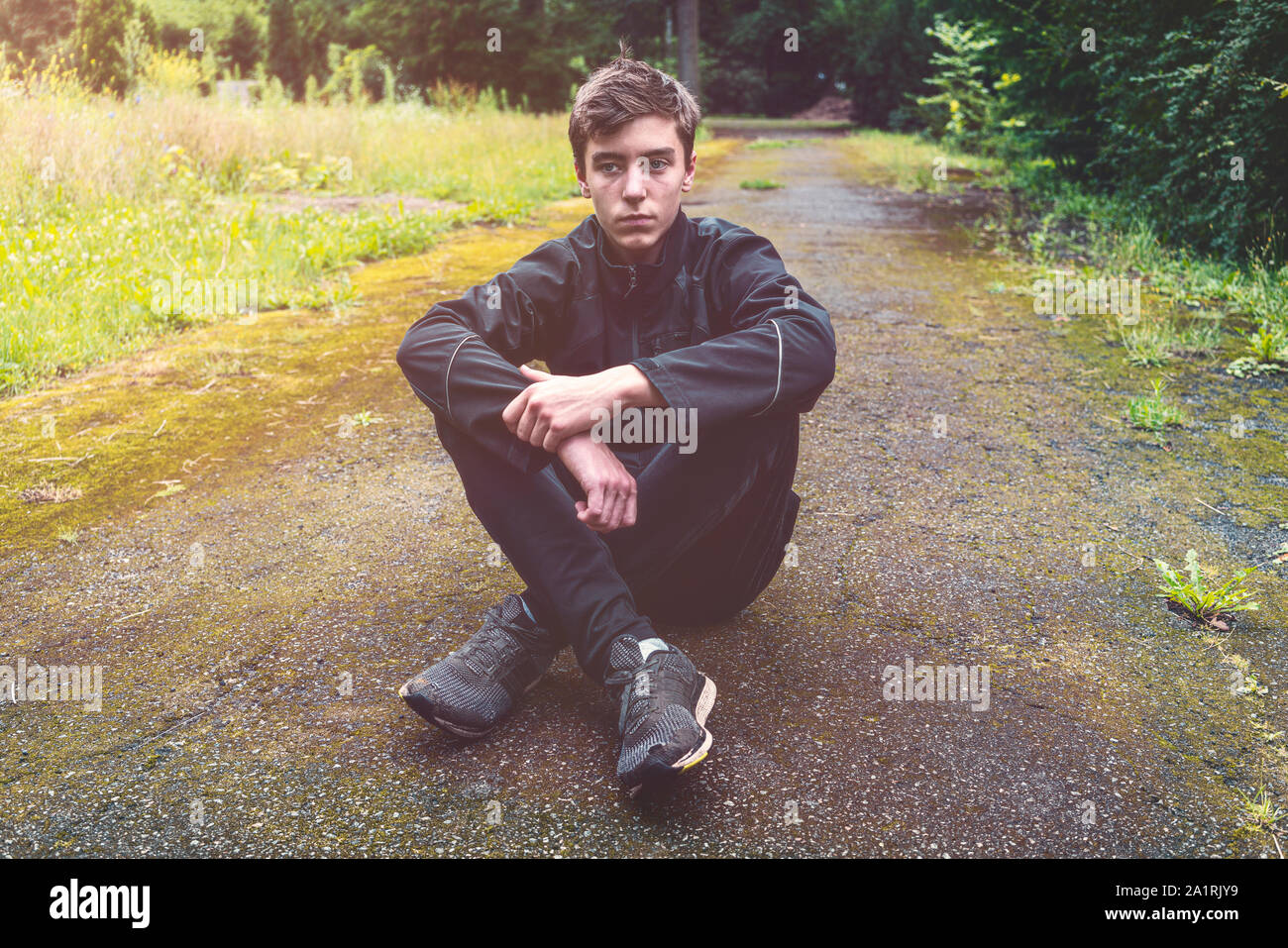 sad young man sitting on the road with crossed legs Stock Photo - Alamy