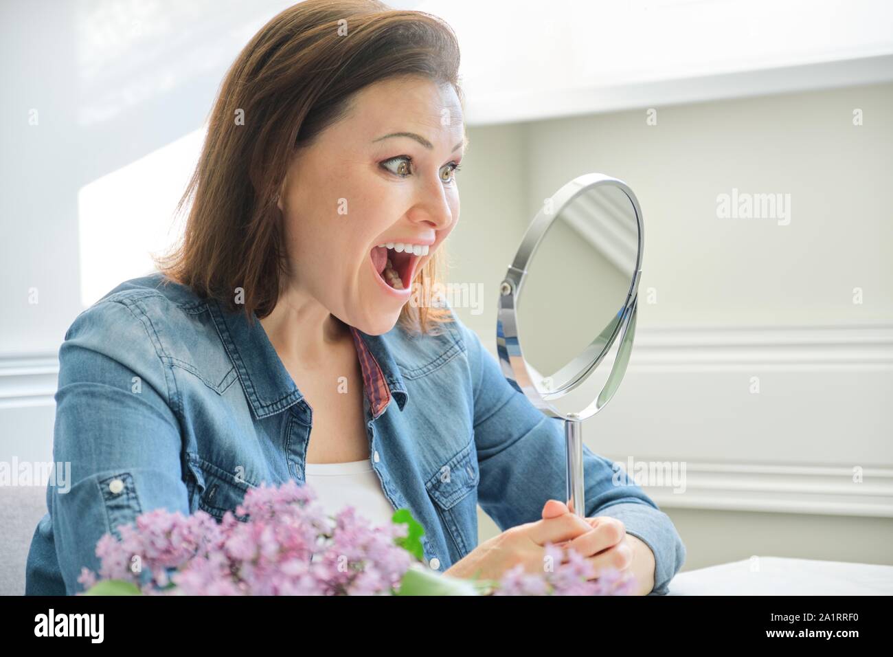 Mature woman looking in the mirror and screaming, massage of mimic ...