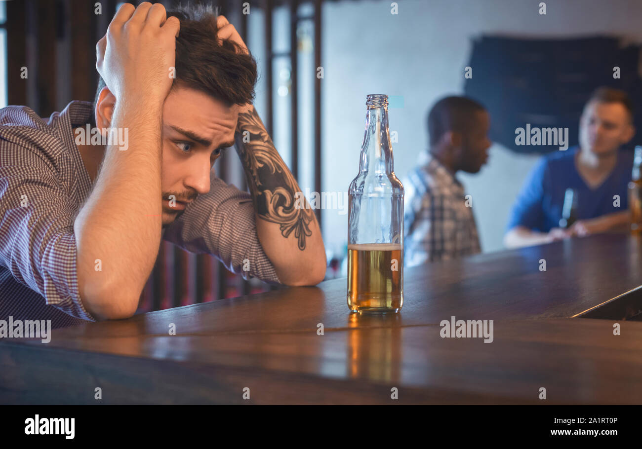 Troubled young man sitting alone at bar Stock Photo - Alamy