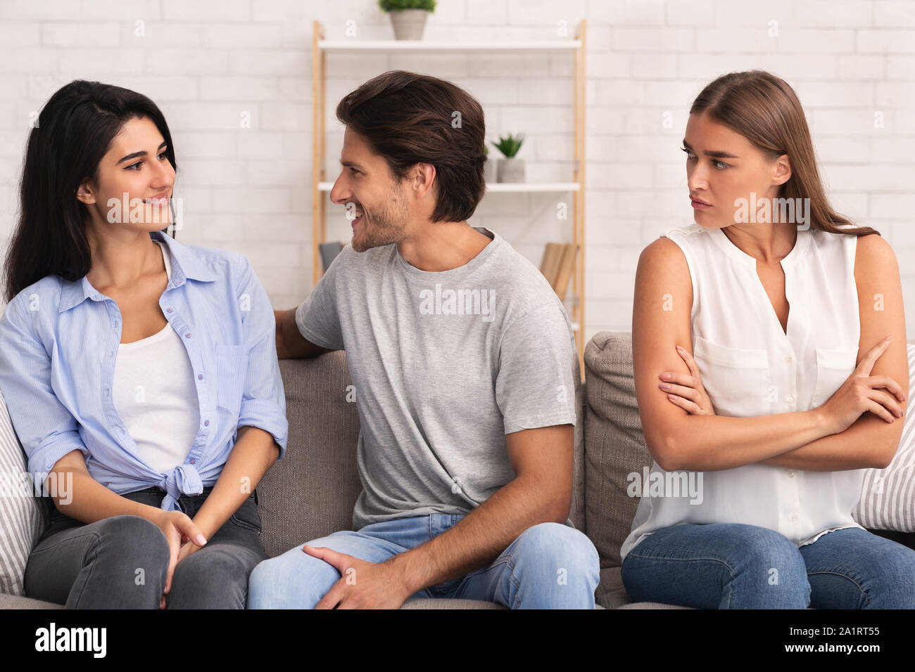 Girlfriend Looking At Boyfriend Flirting With Girl On Sofa Indoor Stock ...