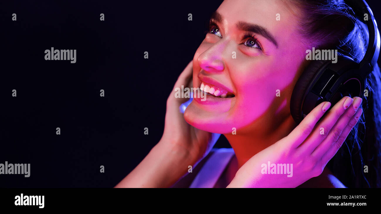 Excited girl listening music in headphones posing in neon lights Stock ...