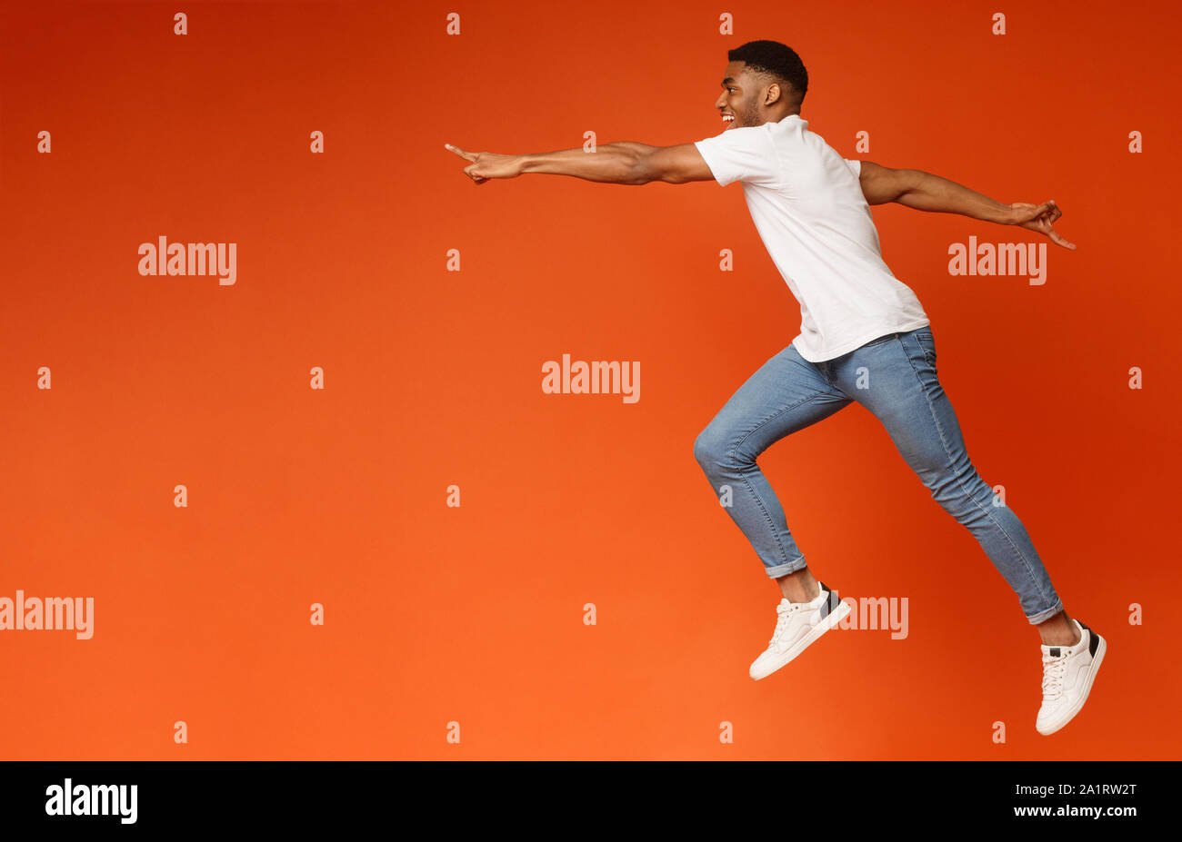 Happy african guy jumping in air, reaching hand aside to free space ...