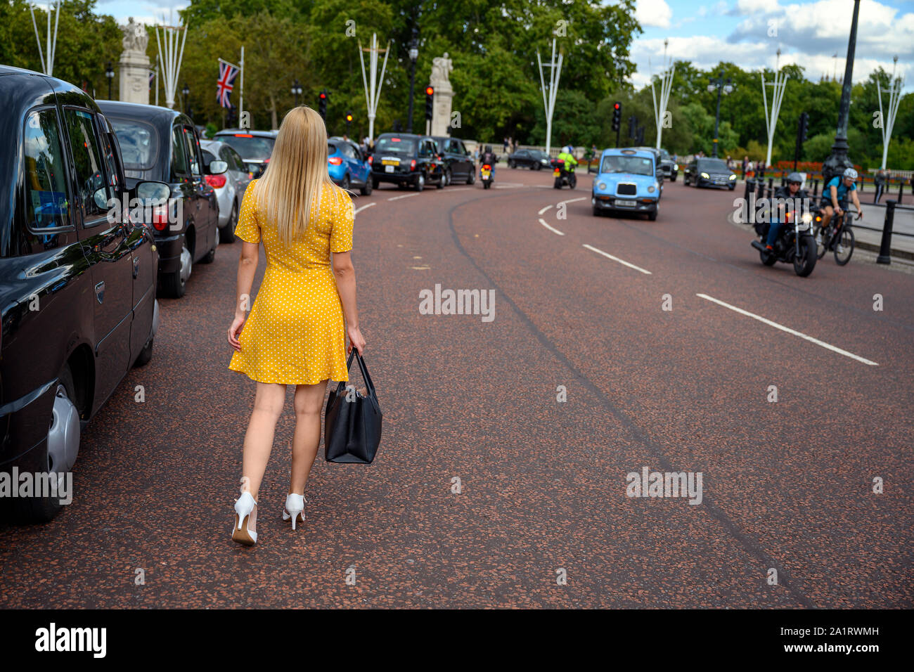 Attractive Young Woman In Yellow Fancy Dress Taking A Taxi Near The Buckingham Palace London attractive-young-woman-in-yellow-fancy-dress-taking-a-taxi-near-the-buckingham-palace-london