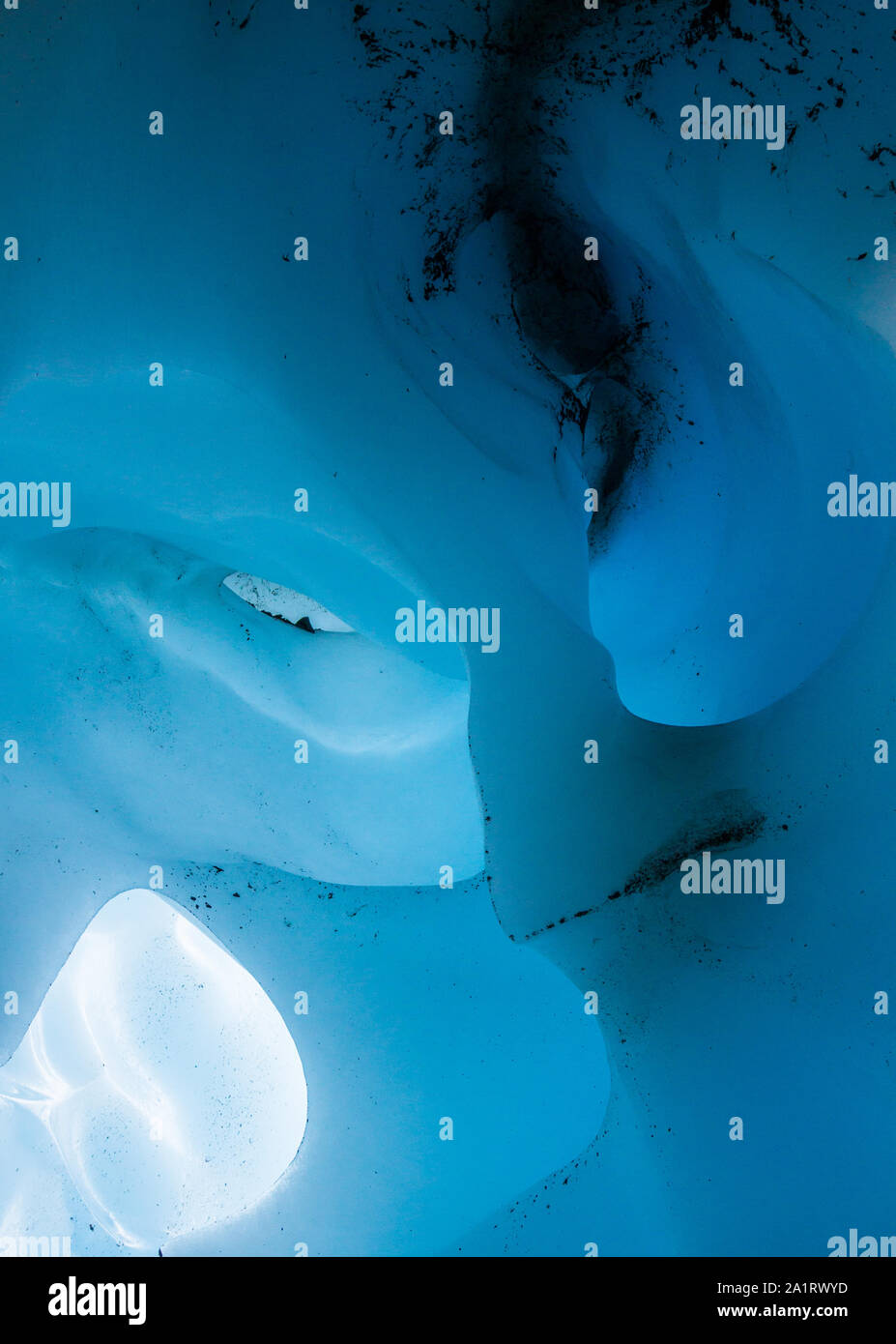 Inside an ice cave, weird shapes and various shades of blue create ...