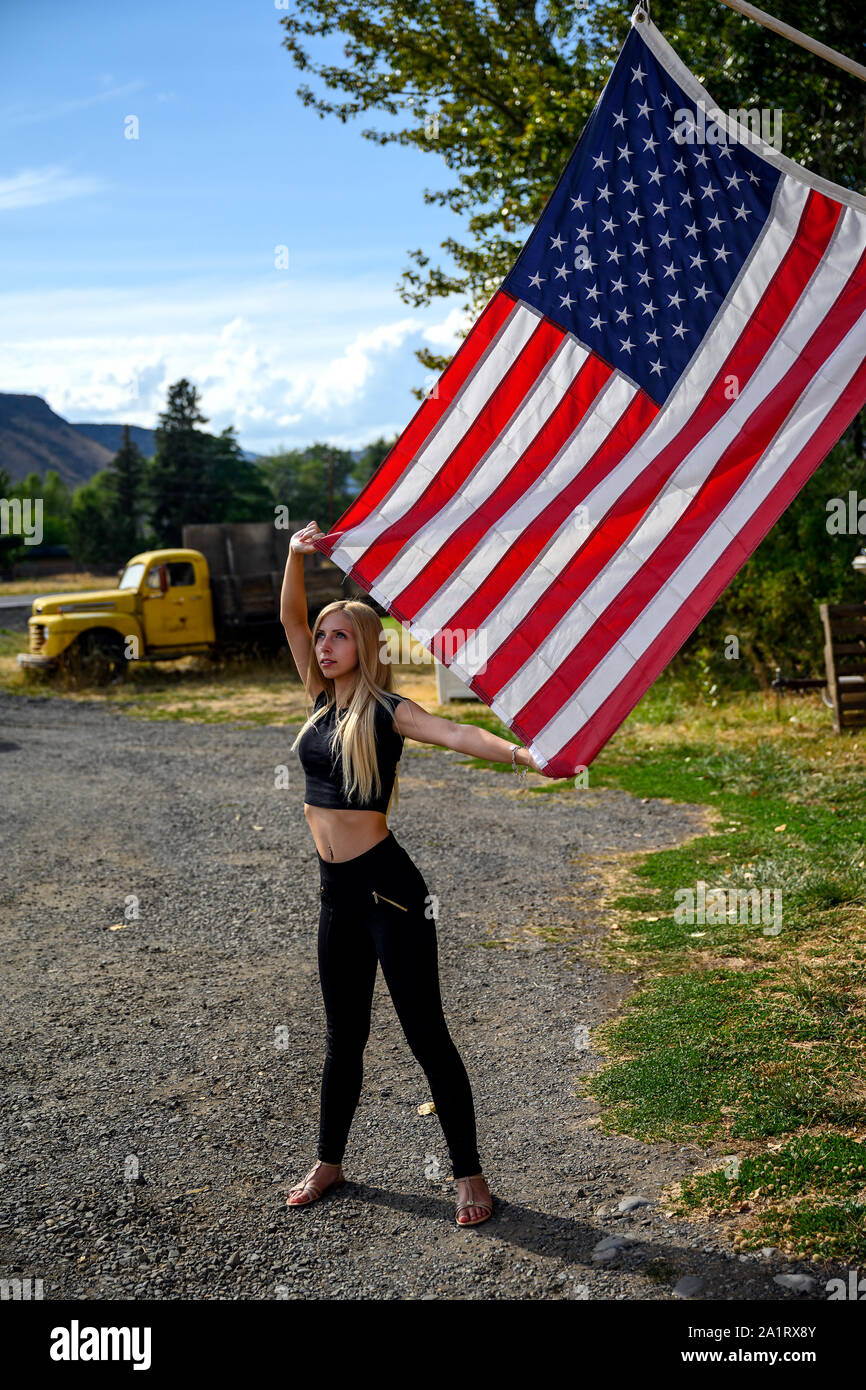 Patriot American woman proudly holding the American flag on her land ...