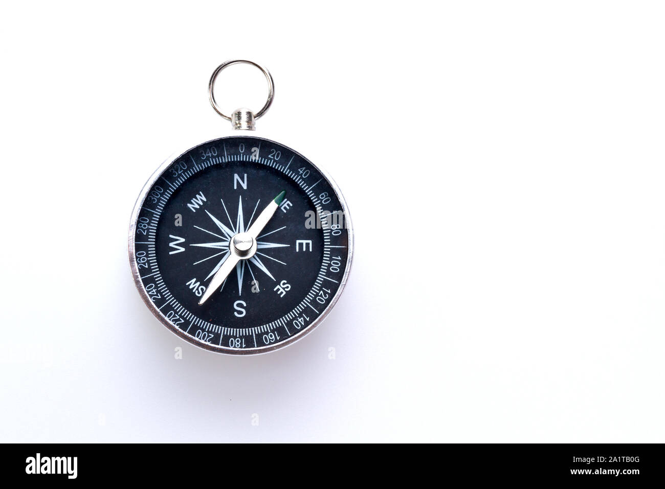 a simple metal compass hanged on white surface with copy space Stock ...