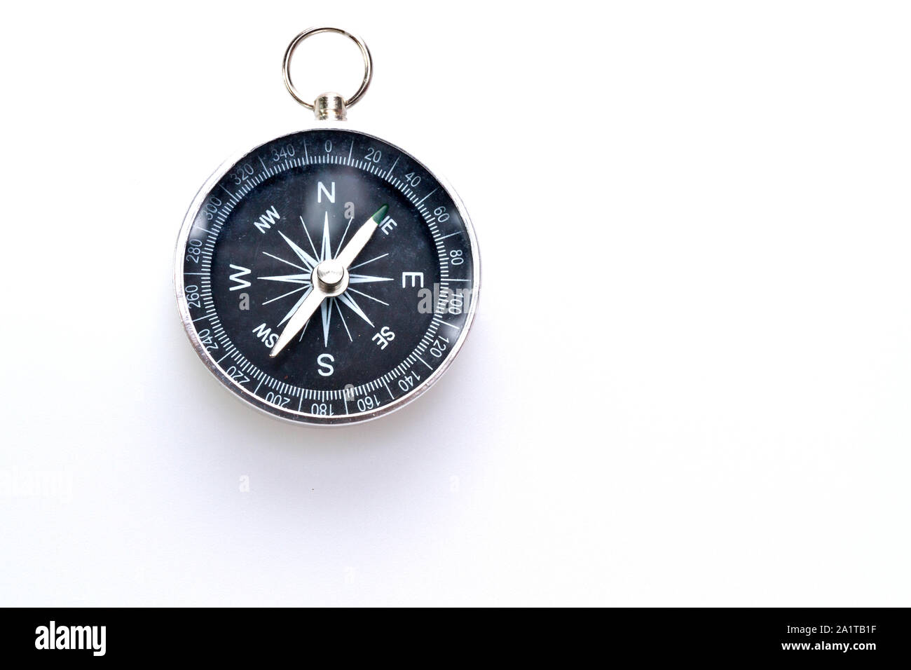 a simple metal compass hanged on white surface with copy space Stock ...