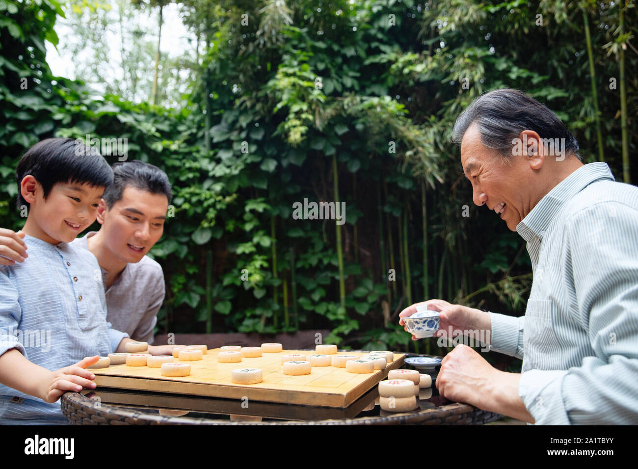 Three people playing chess between the two generations Stock Photo - Alamy