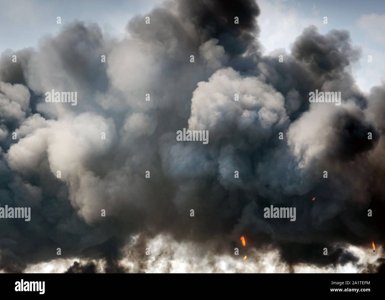 plumes of black smoke fill an otherwise blue sky, after a fiery ...