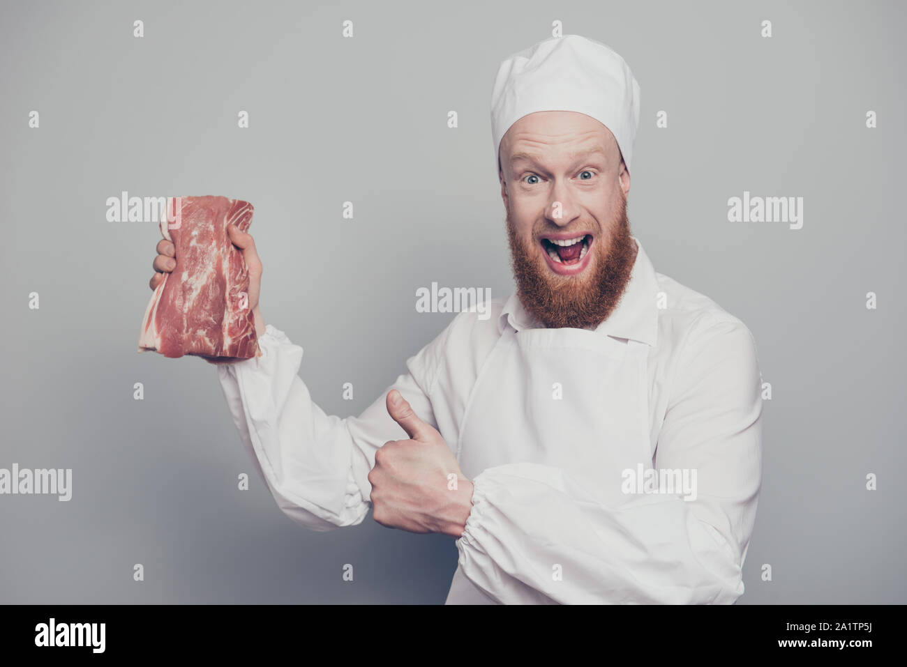 Portrait of he nice crazy funny butcher with stubble holding fresh meat ...