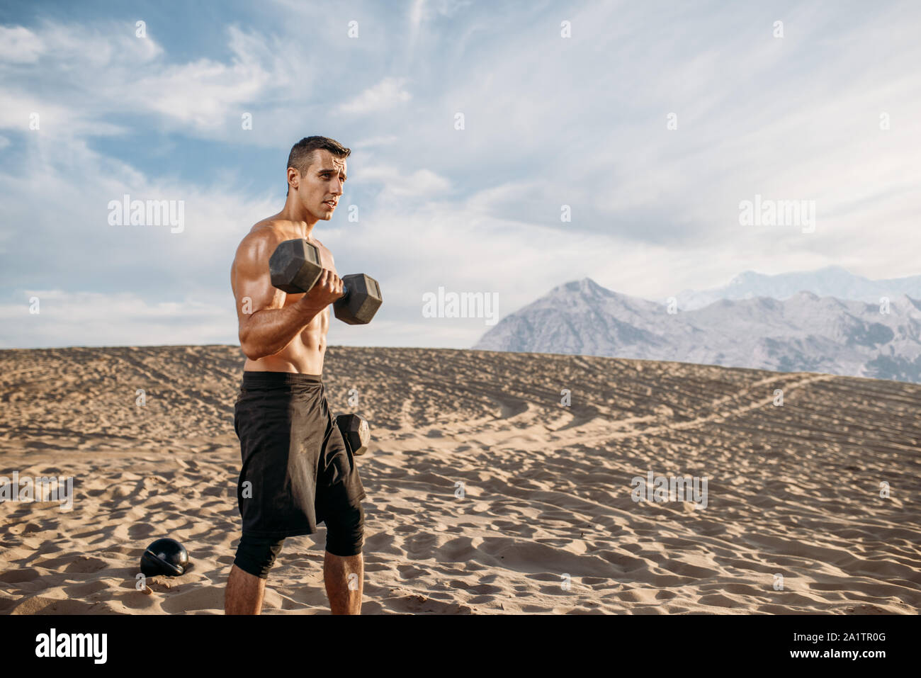 Muscular male athlete with dumbbells in desert Stock Photo - Alamy