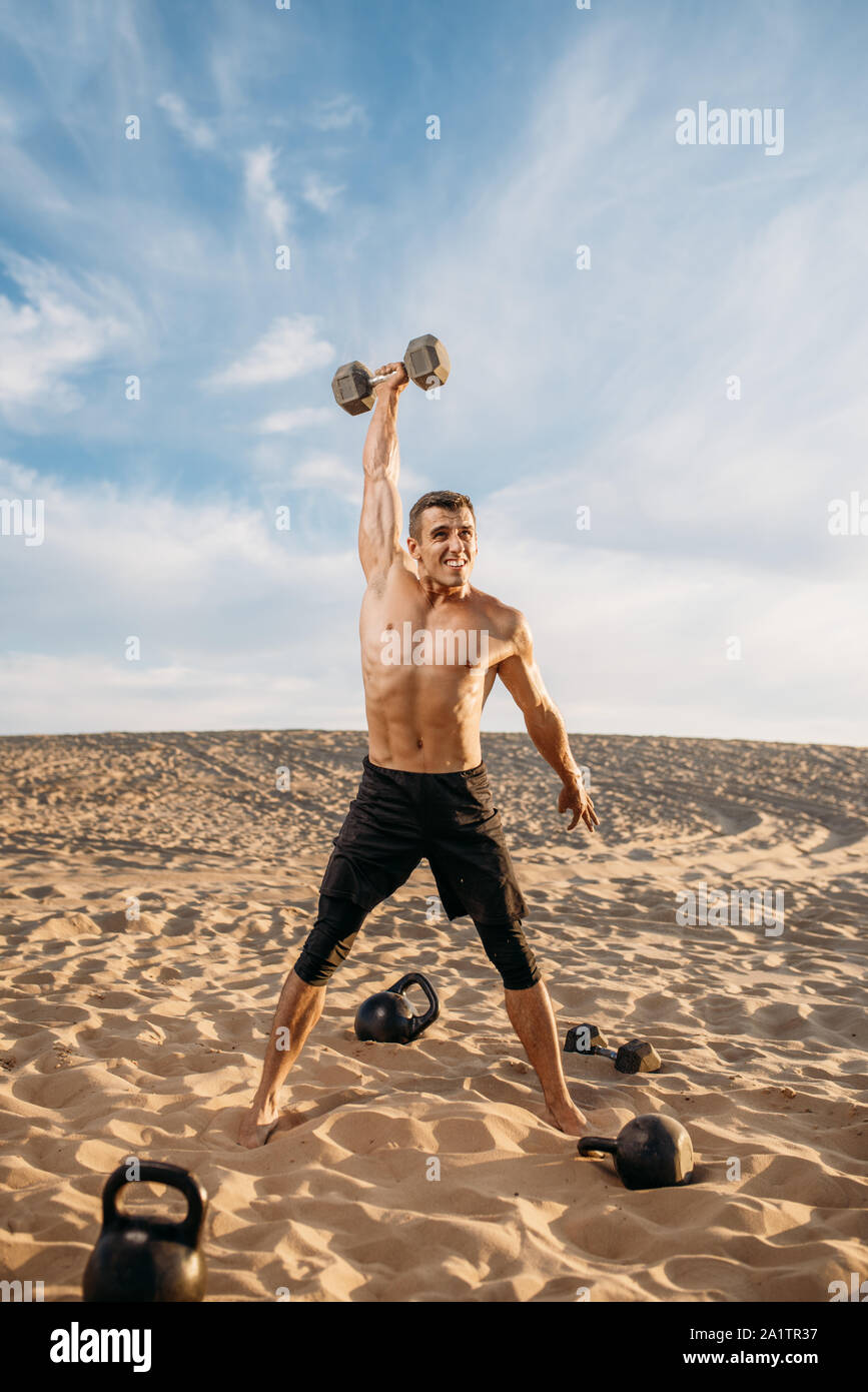Sportsman doing exercise with weights in desert Stock Photo - Alamy