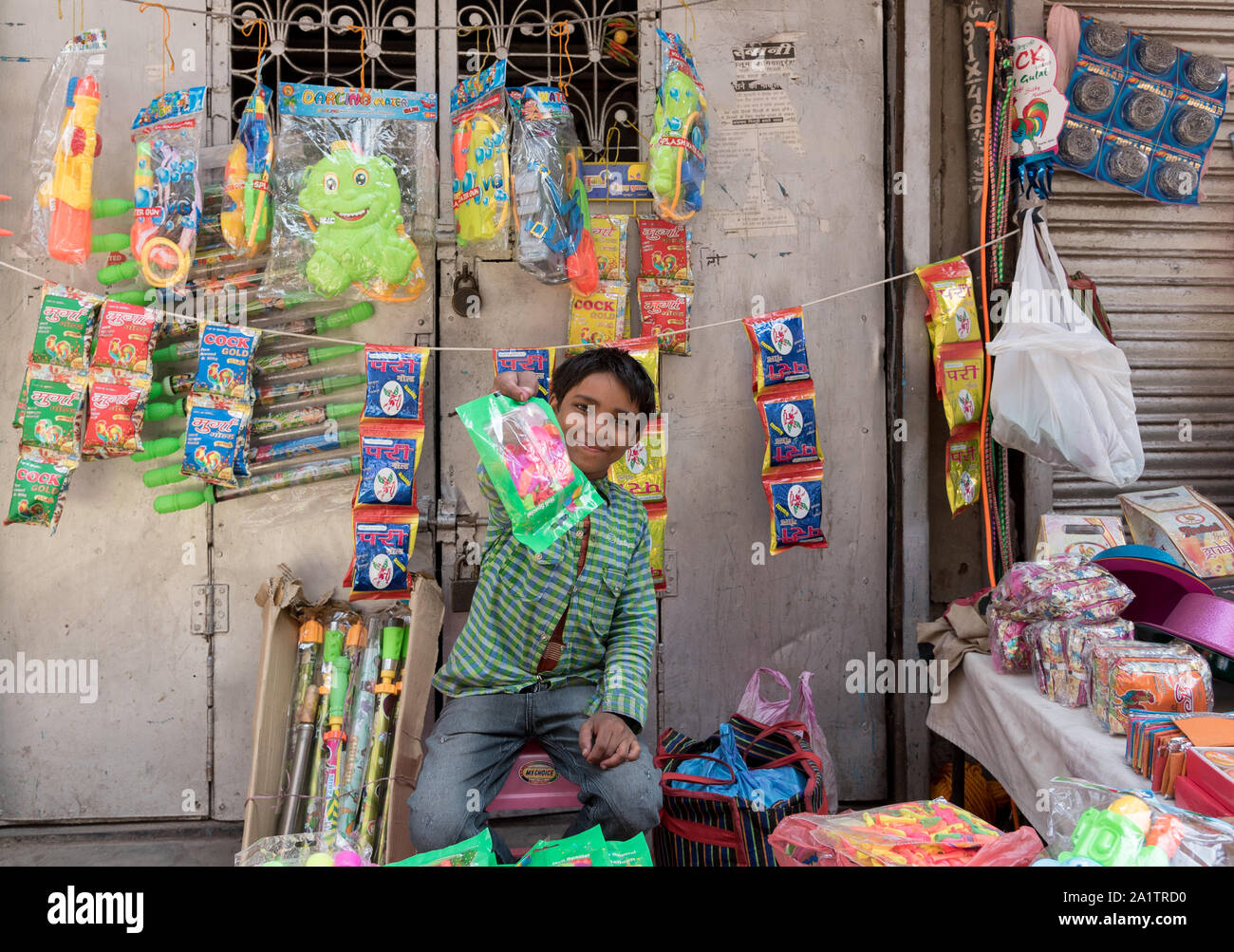 Young boy smiling and selling plastic toys on the streets of New Delhi ...