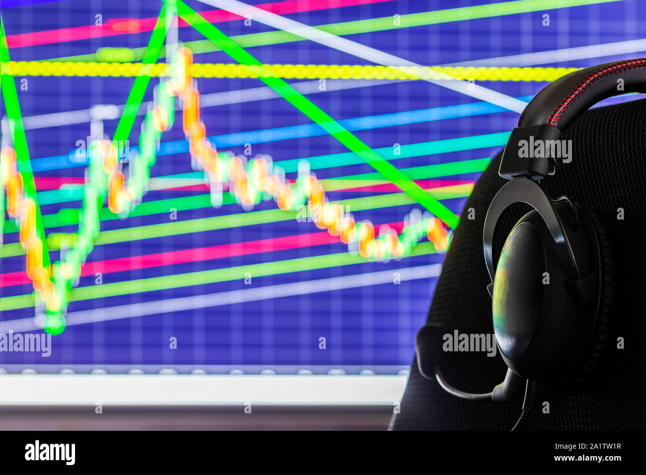 black headset on chair over monitor with trading chart in background ...