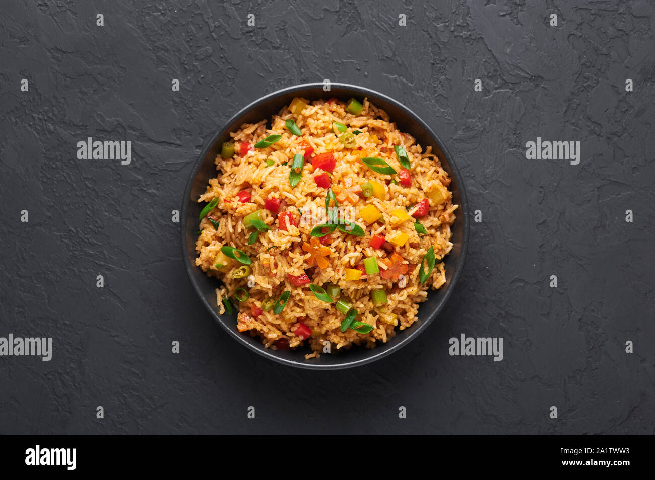 Veg Schezwan Fried Rice in black bowl at dark slate background ...
