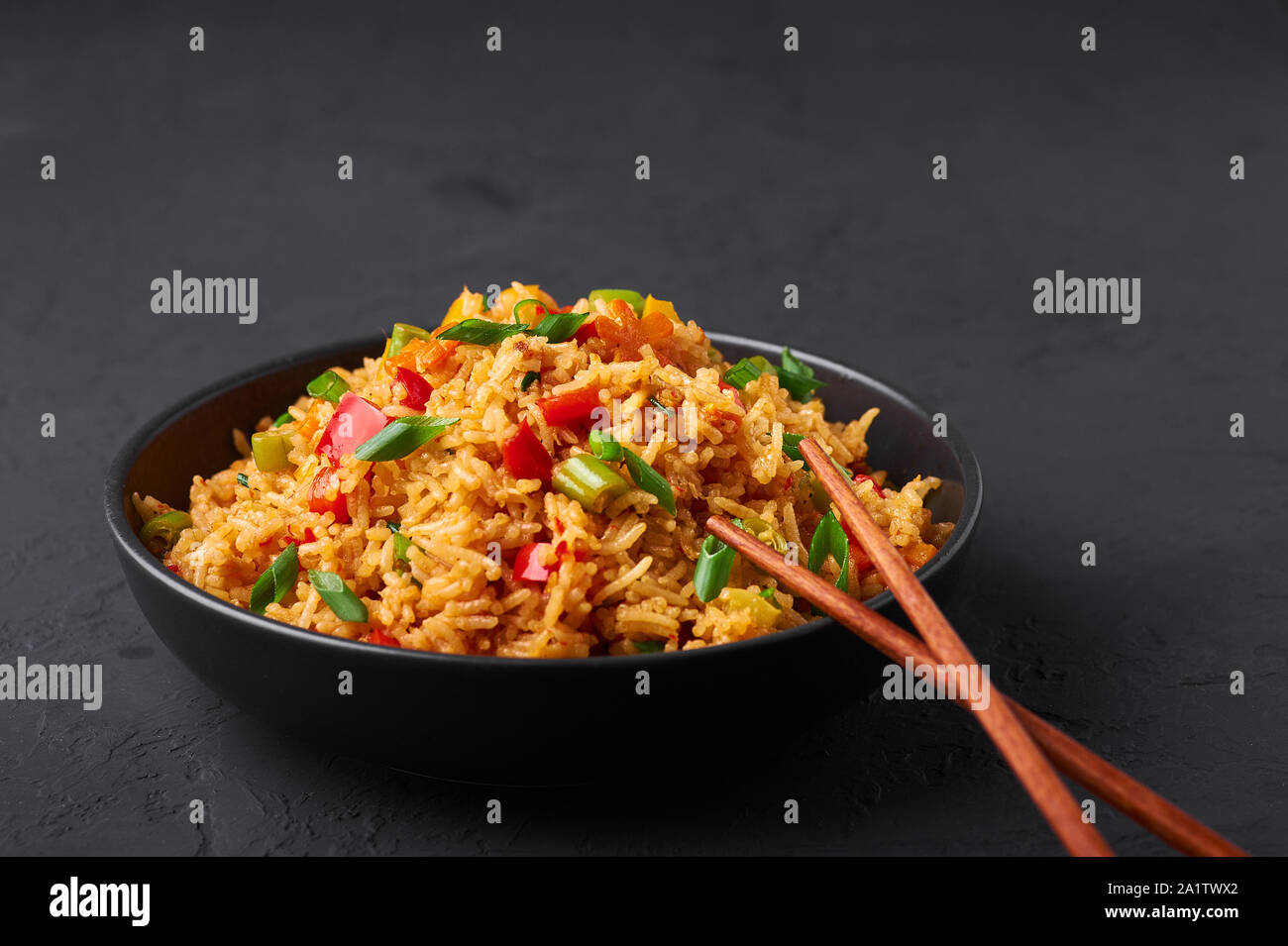 Veg Schezwan Fried Rice in black bowl at dark slate background ...