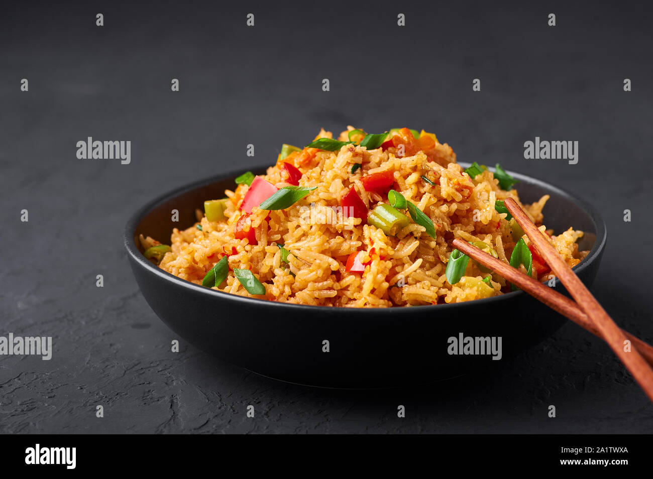 Veg Schezwan Fried Rice in black bowl at dark slate background ...