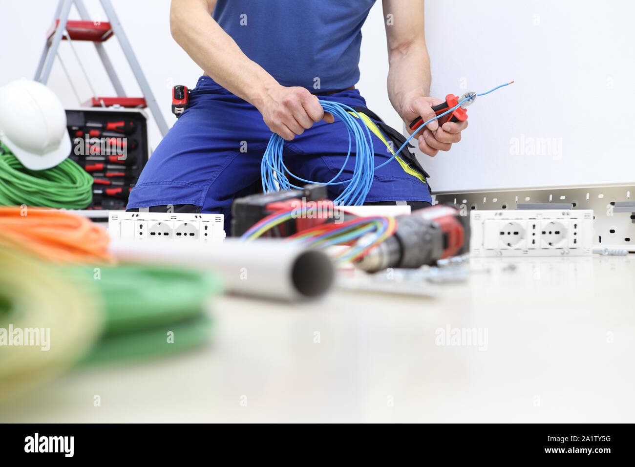 electrician at work with nippers in hand cut the electric cable ...