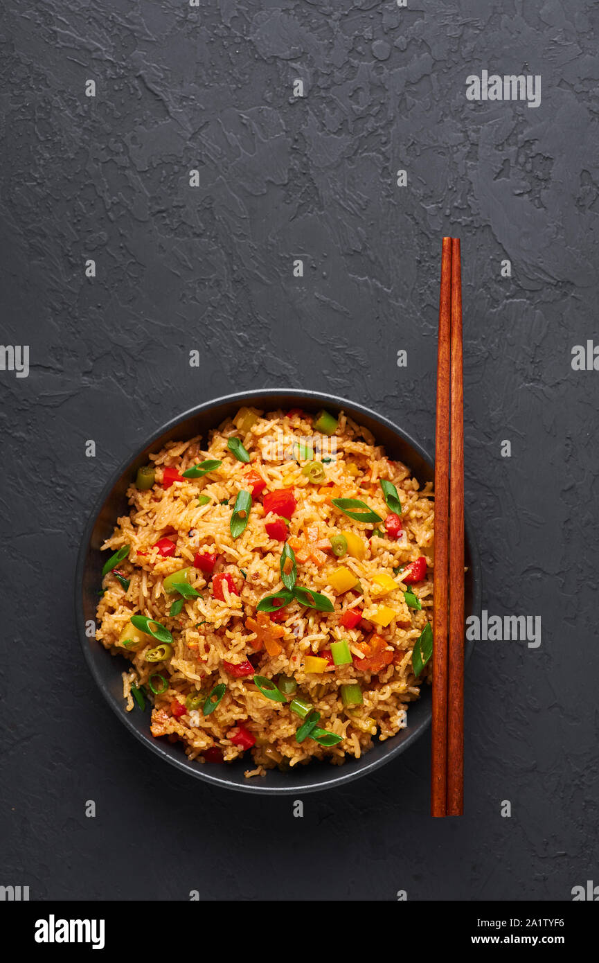 Veg Schezwan Fried Rice in black bowl at dark slate background ...