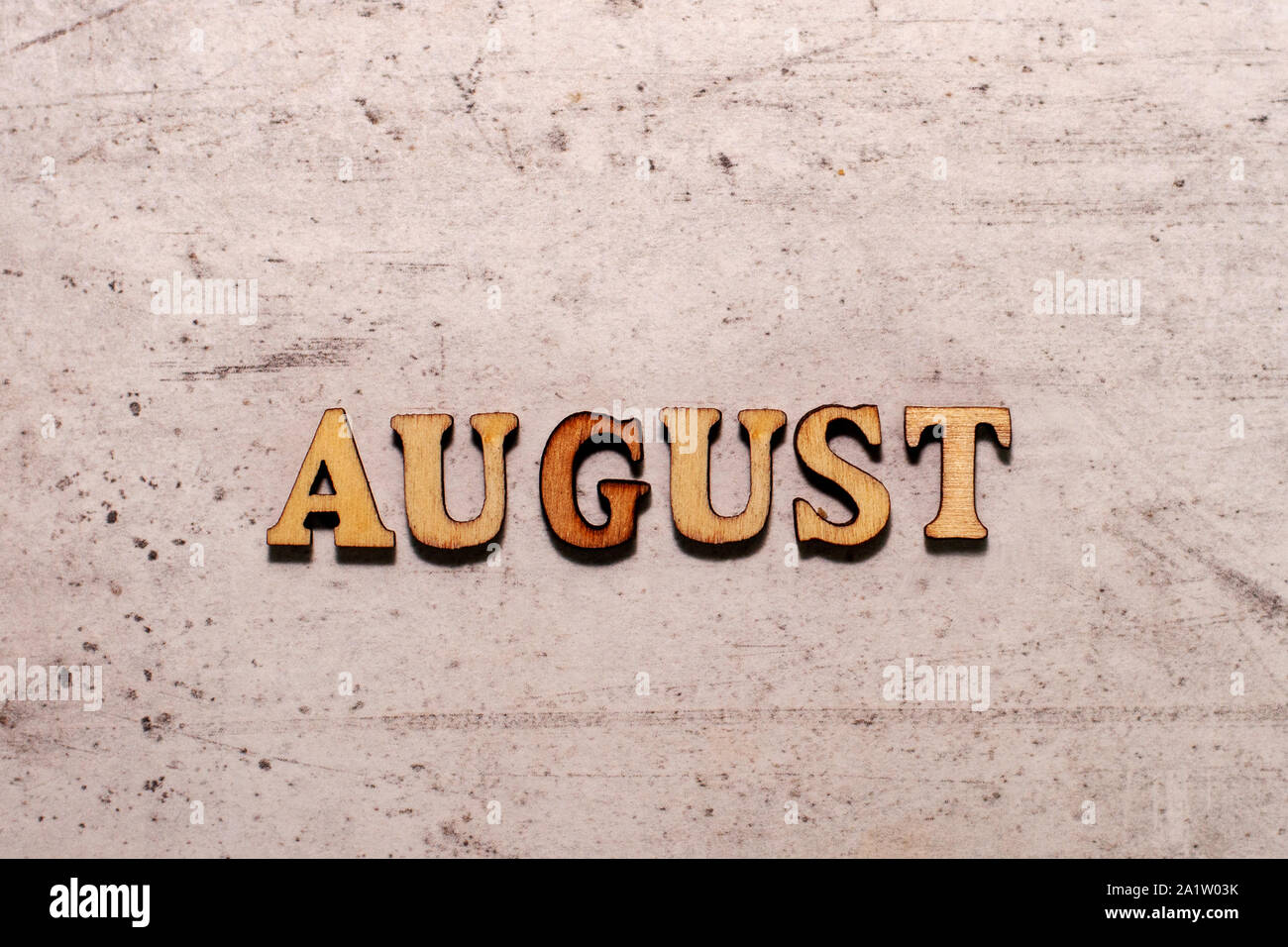 The word August laid out in wooden letters on a light background. Close ...