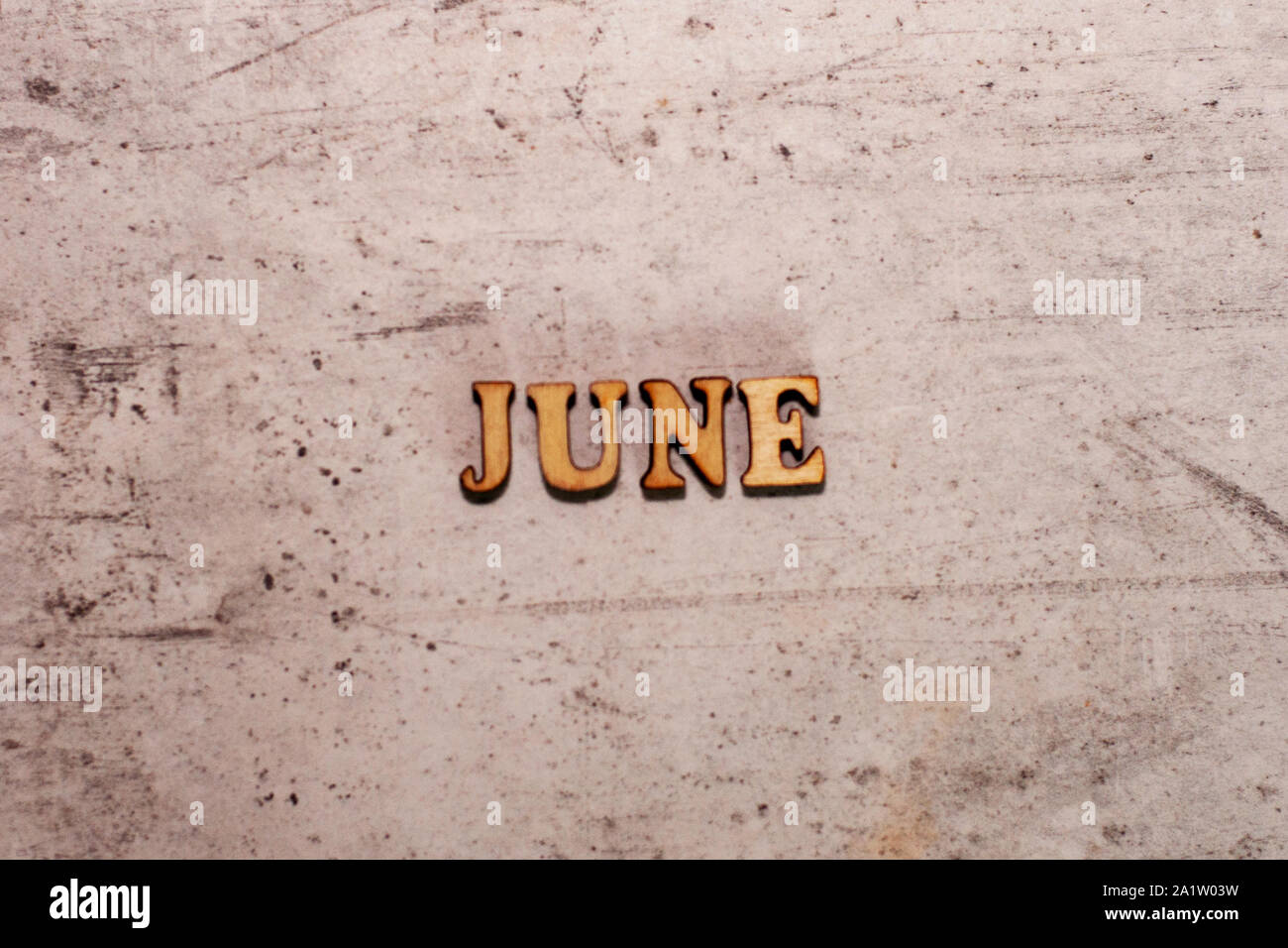 The word June laid out in wooden letters on a light background. Close ...