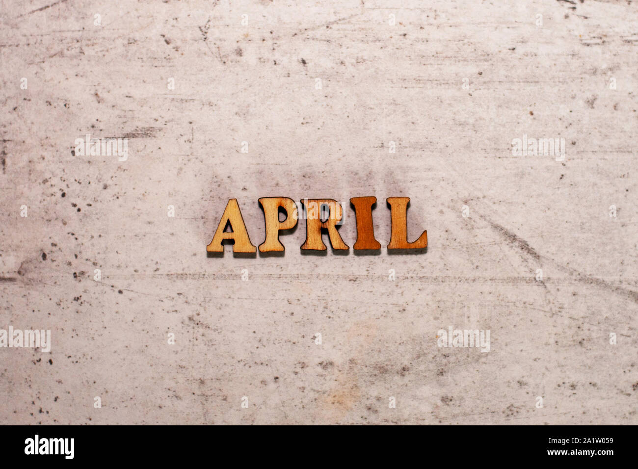 The word April laid out in wooden letters on a light background. Close ...