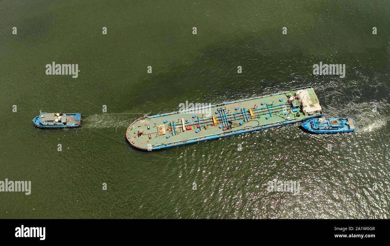 Tugs pulling heavy barge on the river top view. Tugs and cargo ship on ...
