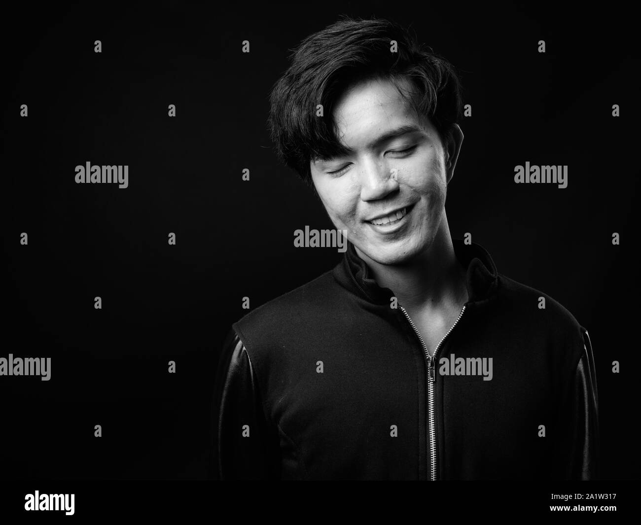 Young handsome Asian man against black background Stock Photo - Alamy