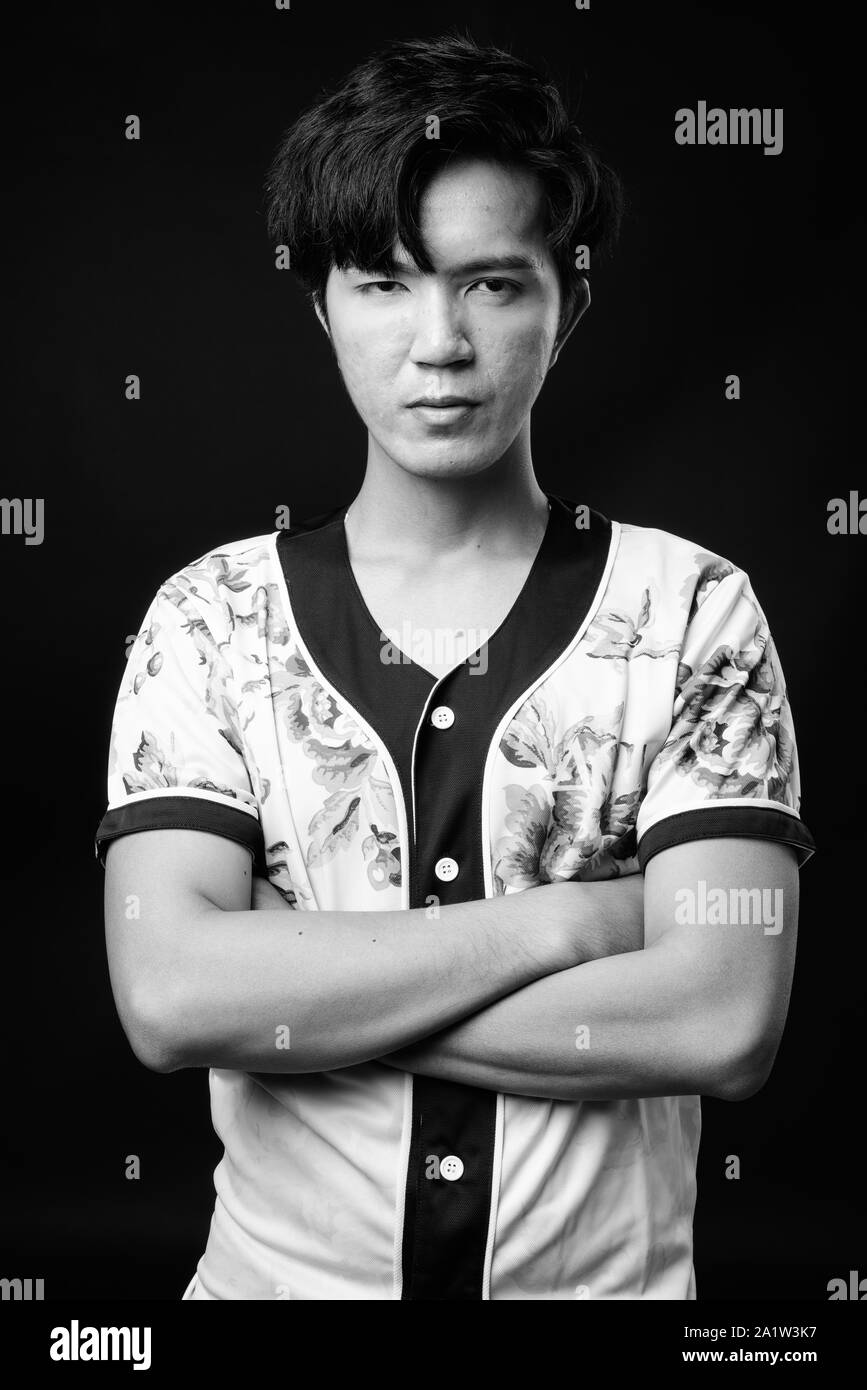 Young handsome Asian man against black background Stock Photo - Alamy