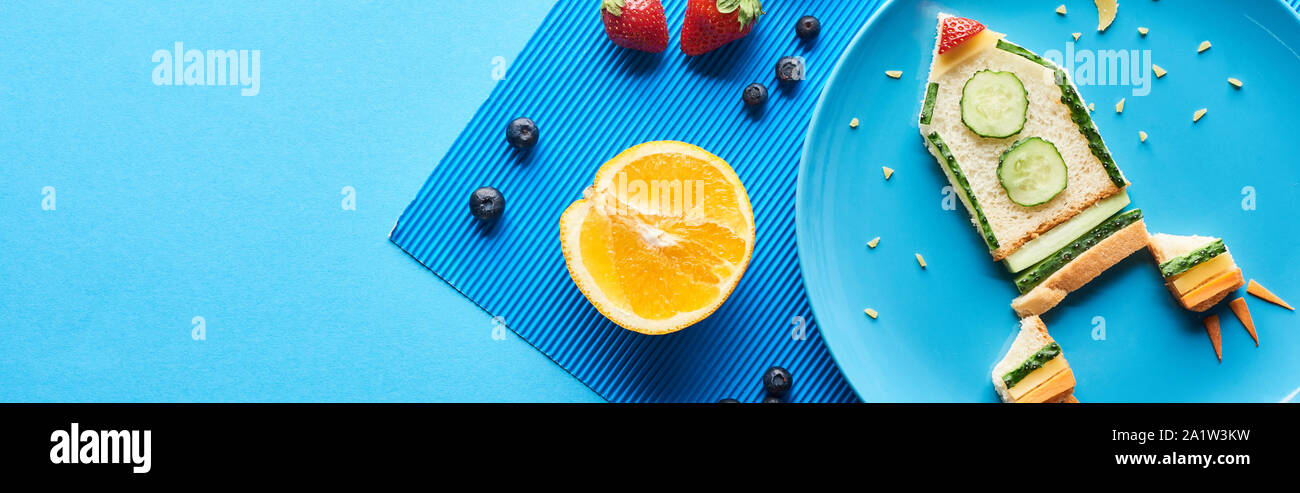 top view of plates with fancy rocket made of food on blue background ...