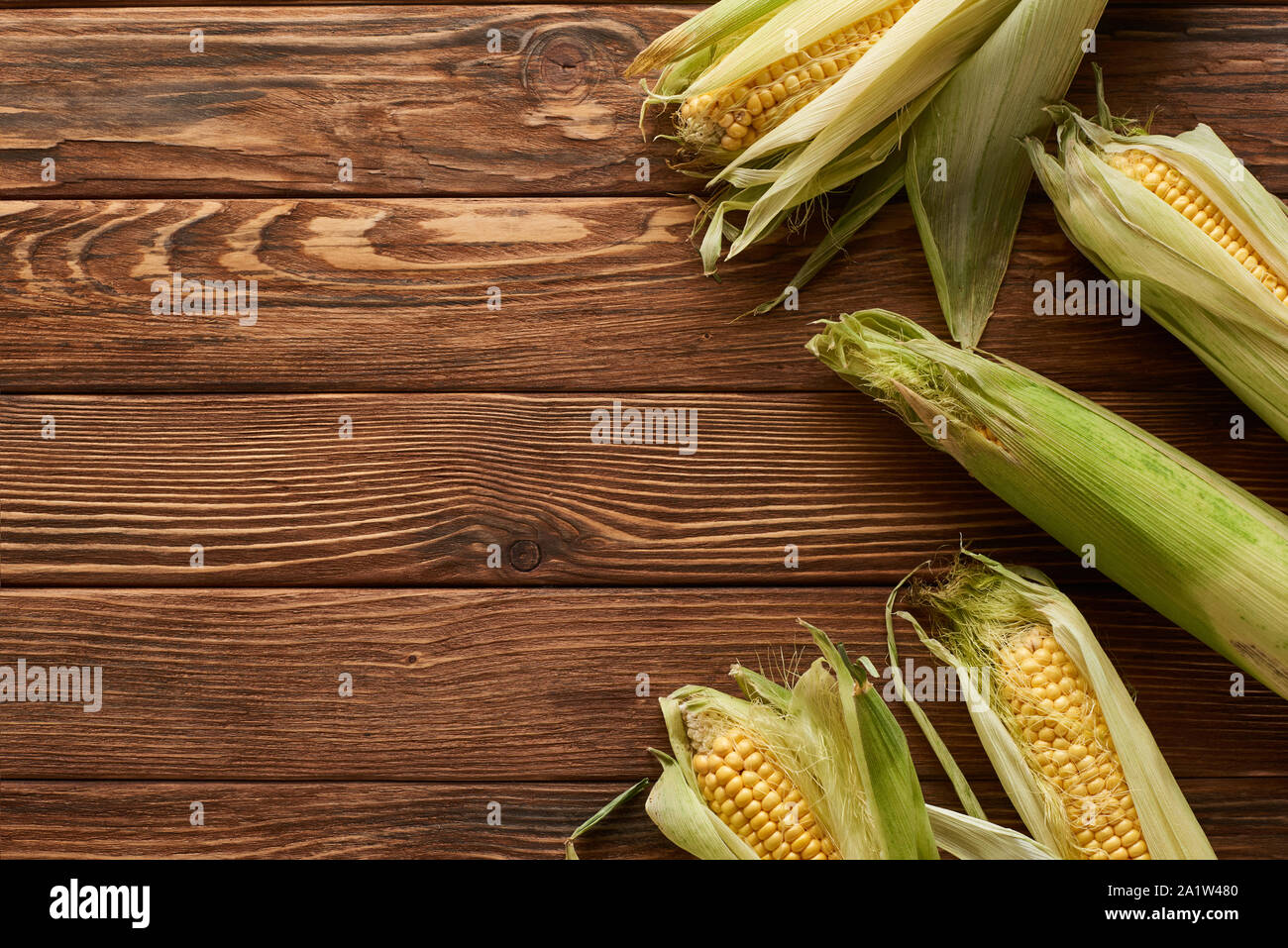 top view of raw sweet corn on brown wooden surface Stock Photo - Alamy