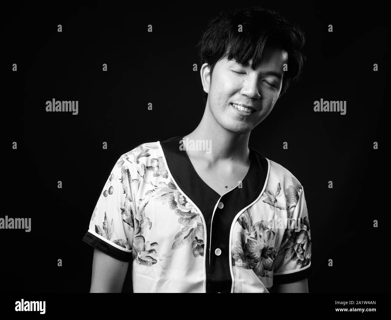 Young handsome Asian man against black background Stock Photo - Alamy