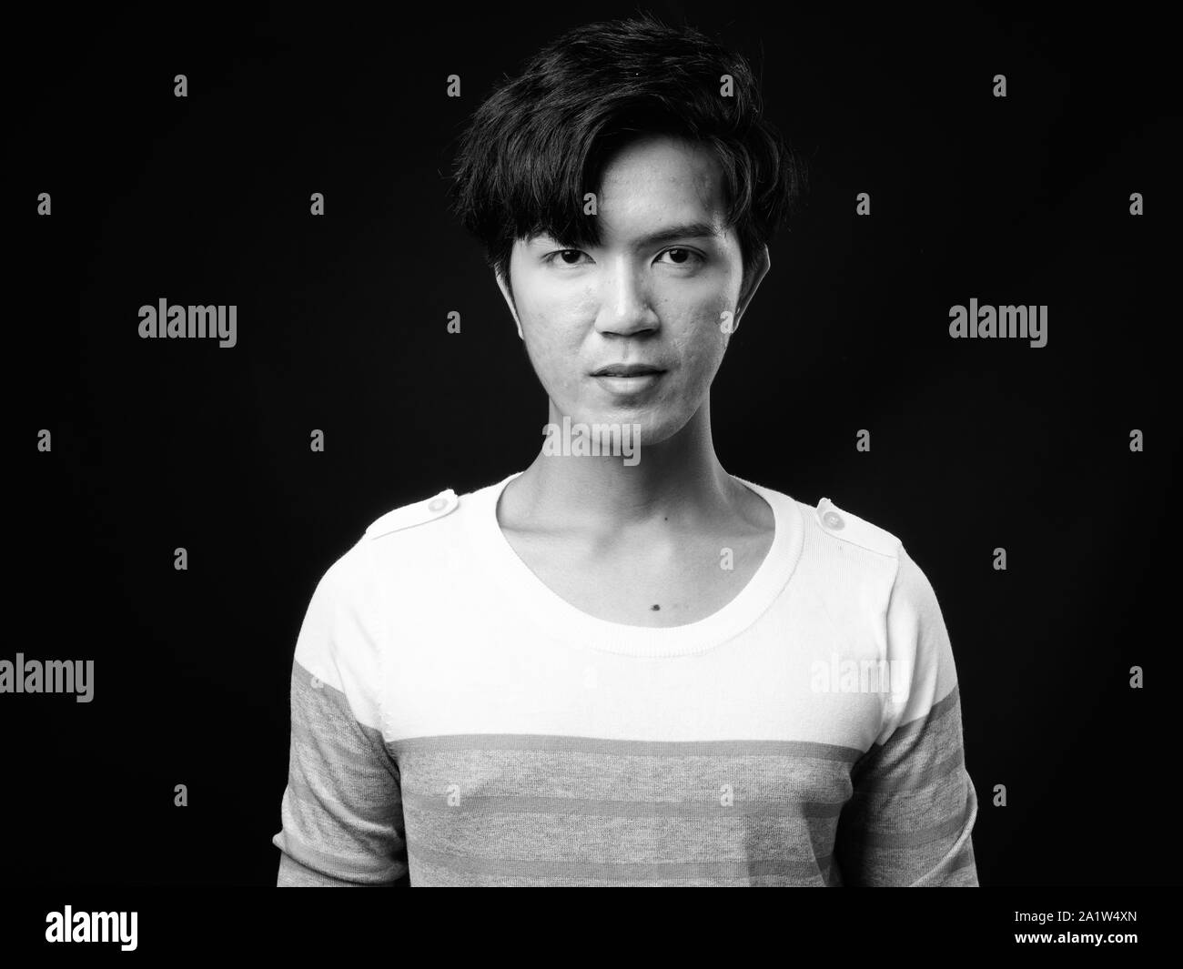 Young handsome Asian man against black background Stock Photo - Alamy