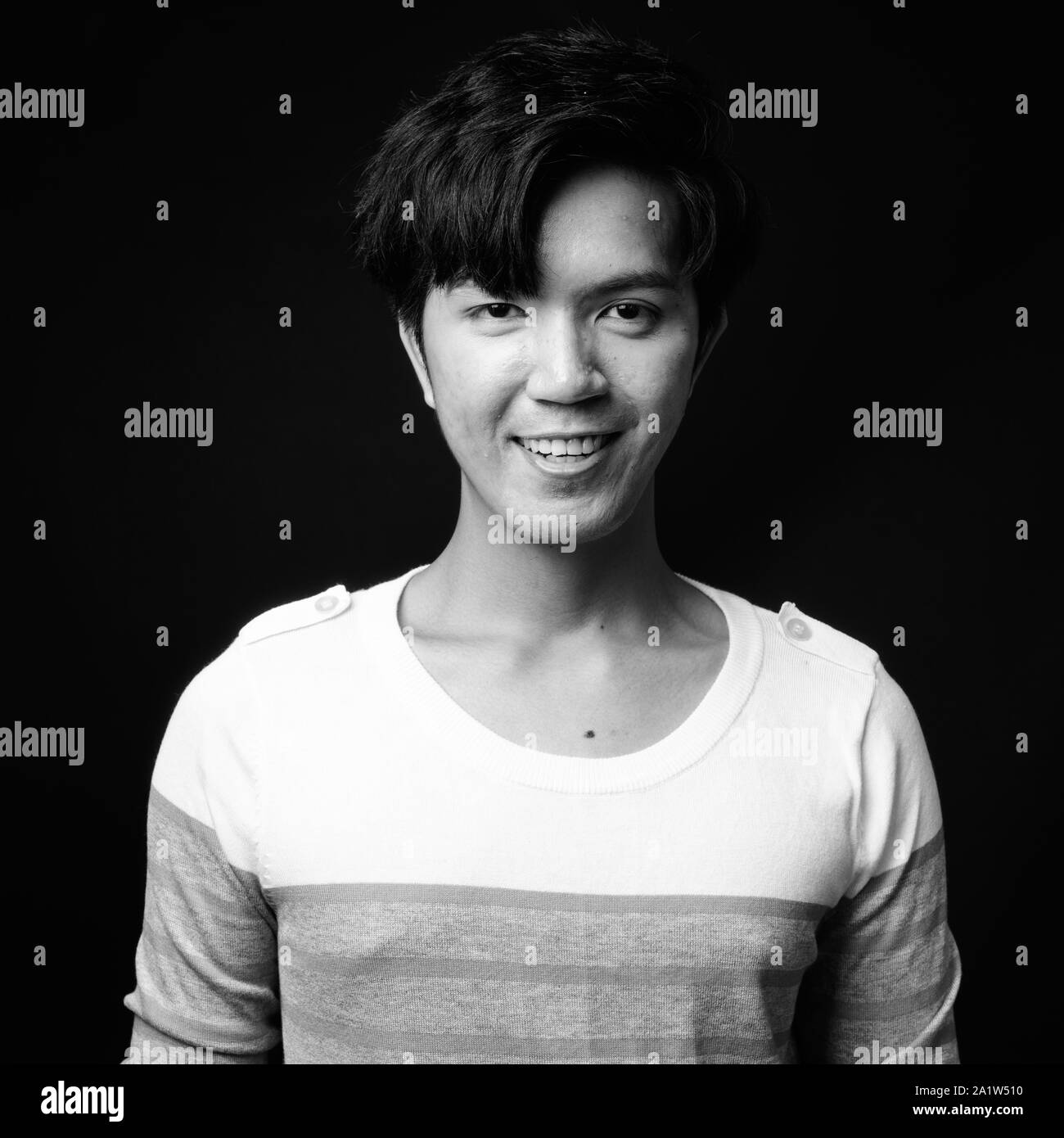 Young handsome Asian man smiling against black background Stock Photo ...