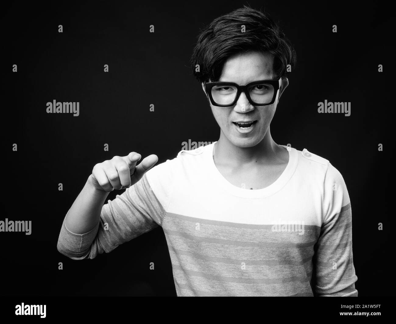 Angry Asian man pointing finger against black background Stock Photo ...