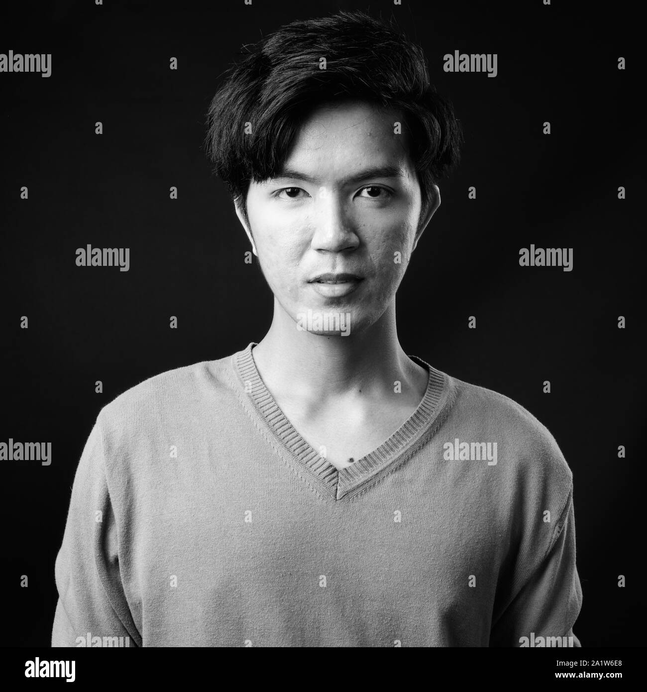 Young handsome Asian man against black background Stock Photo - Alamy
