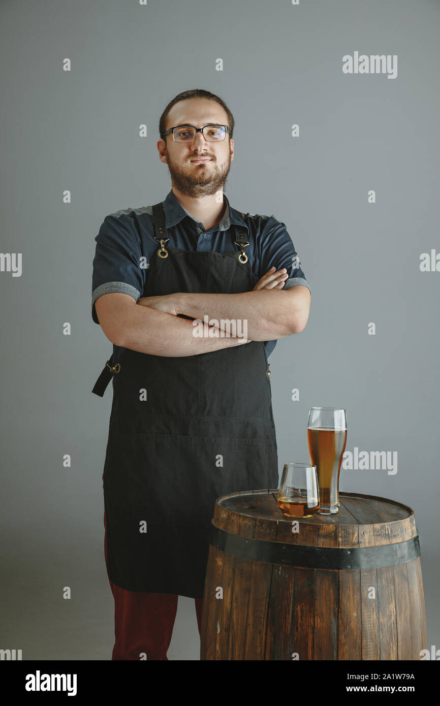Confident young male brewer with self crafted beer in glass on wooden ...