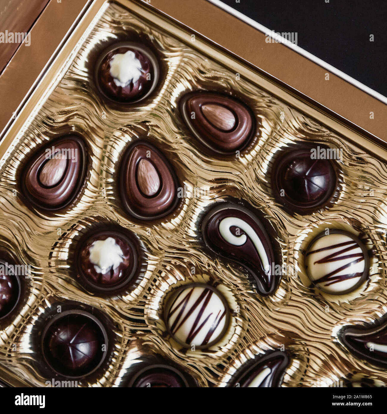 Chocolate candies of different shapes in a gold box, View from above ...
