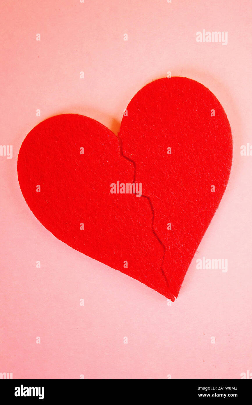 Red felt heart broken into two halves on a pink background Stock Photo ...