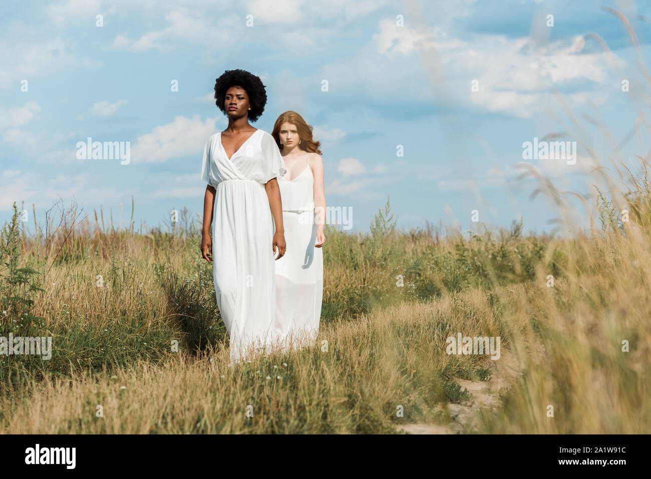 selective focus of pretty multicultural girls walking on path near ...