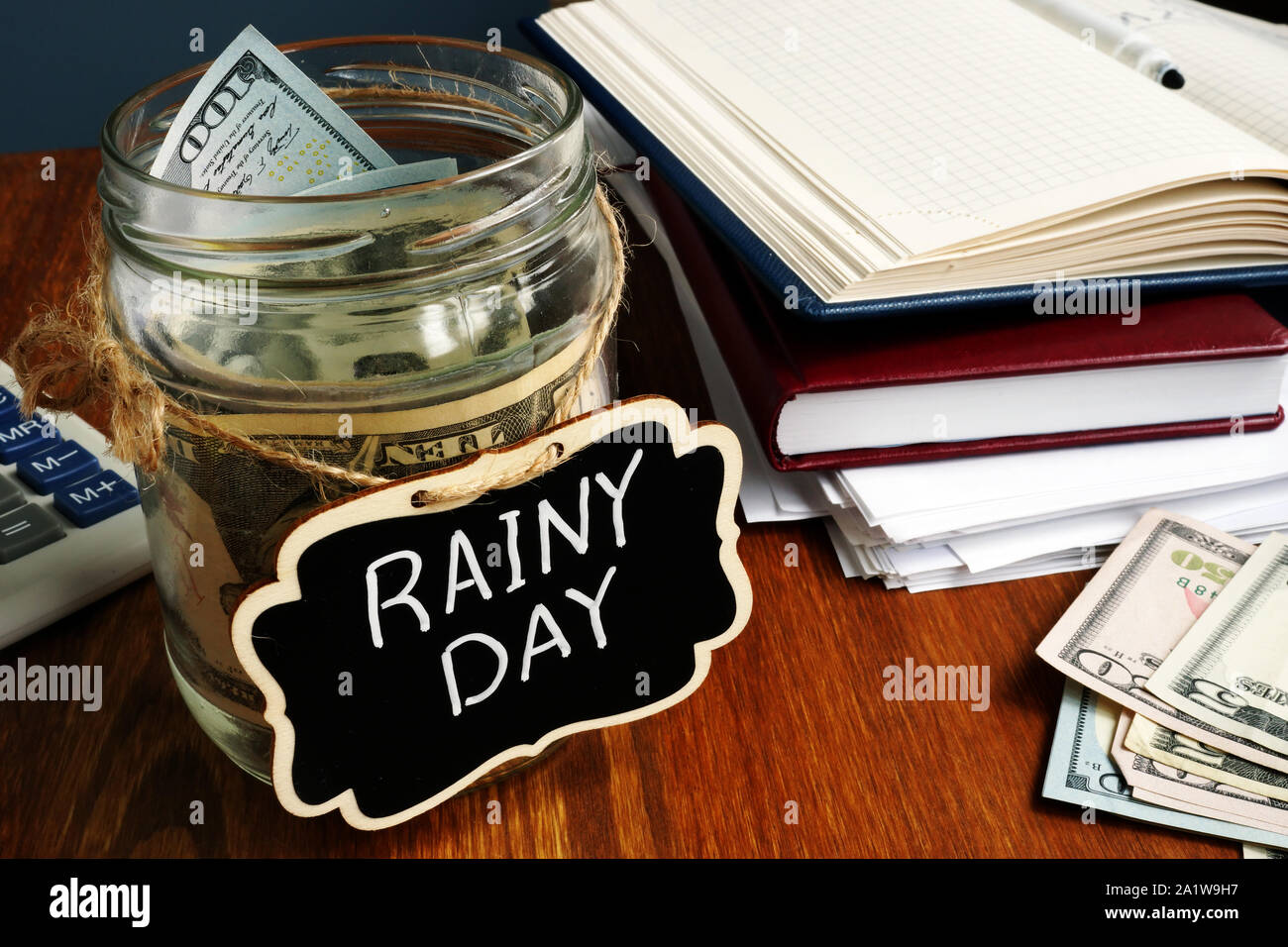 Rainy Day Fund label on the jar with money Stock Photo - Alamy