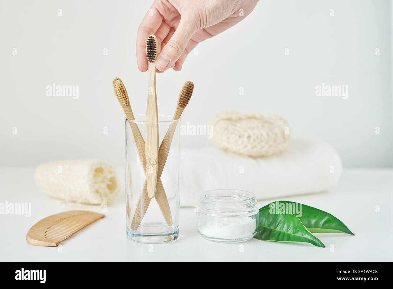 Woman hand take wooden bamboo toothbrush in bathroom interior. No ...