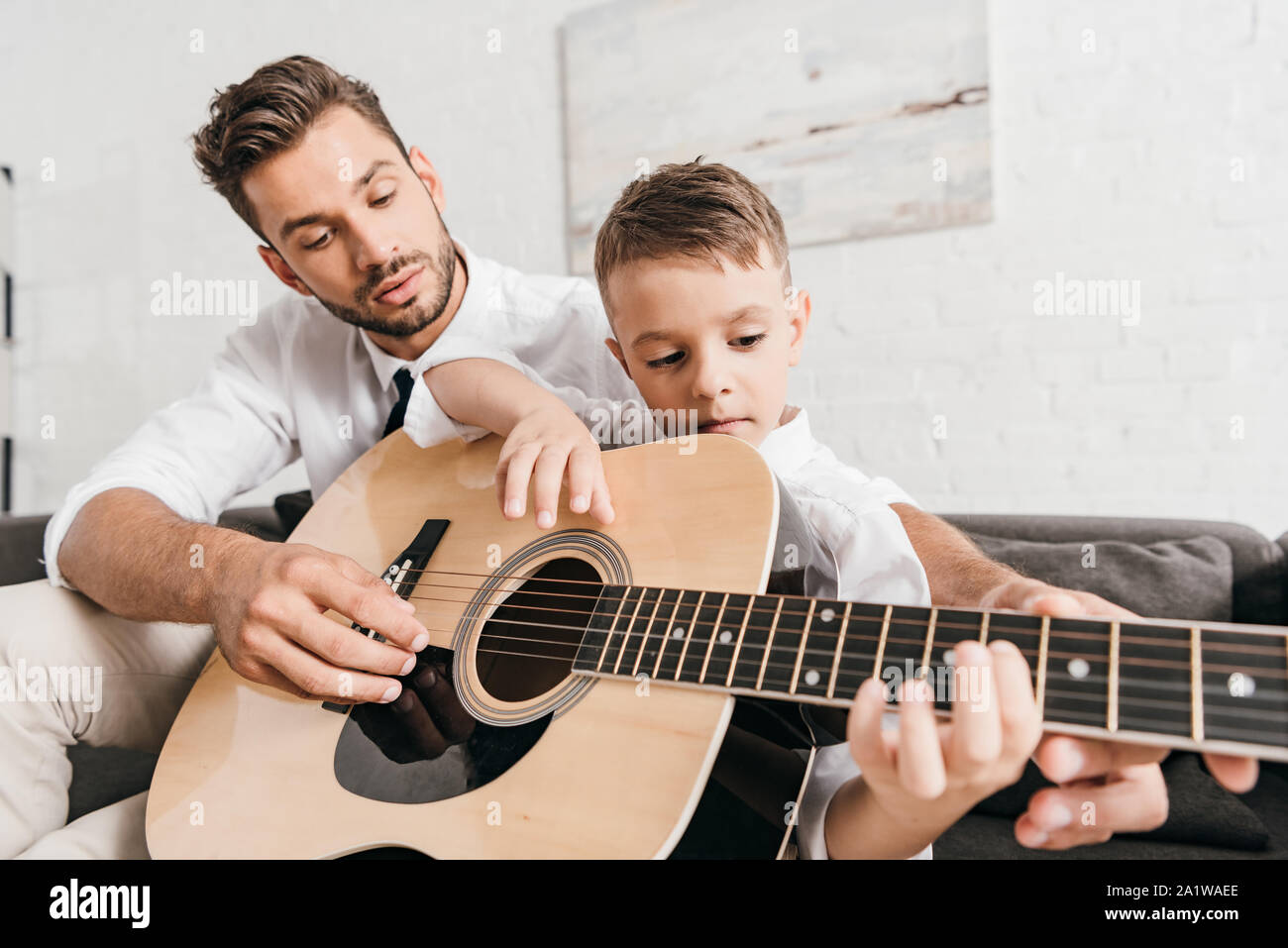dad teaching son to play acoustic guitar at home Stock Photo - Alamy