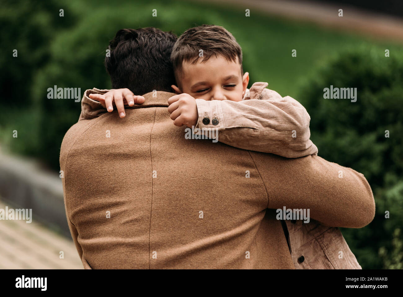 back view of father embracing son on street in autumn day Stock Photo ...