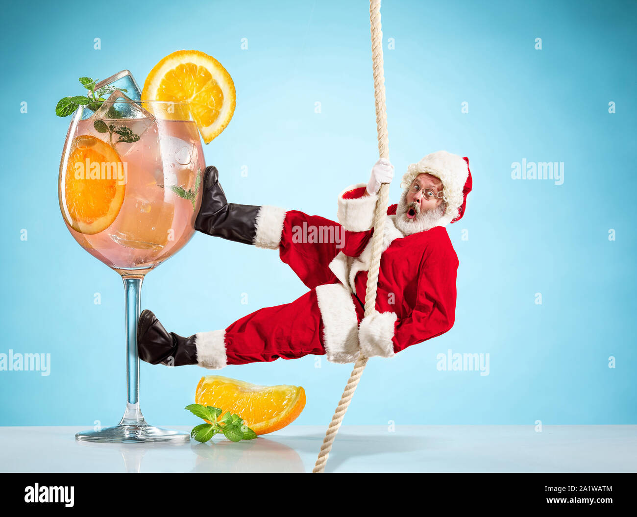 Happy Christmas Santa Claus climbing on rope near by cocktail on blue ...