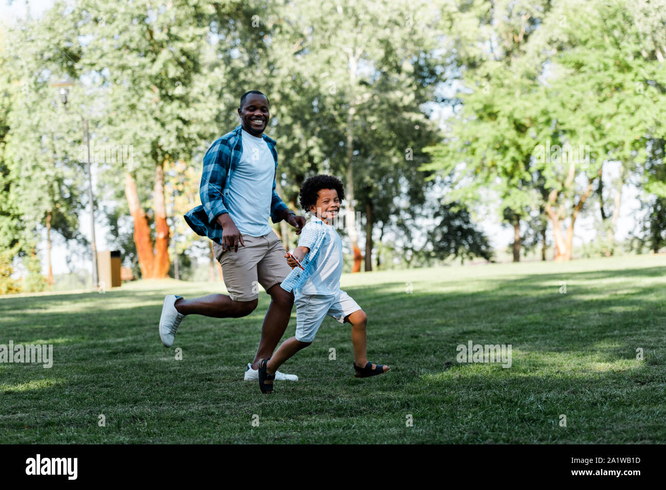happy african american father and son running on grass Stock Photo - Alamy