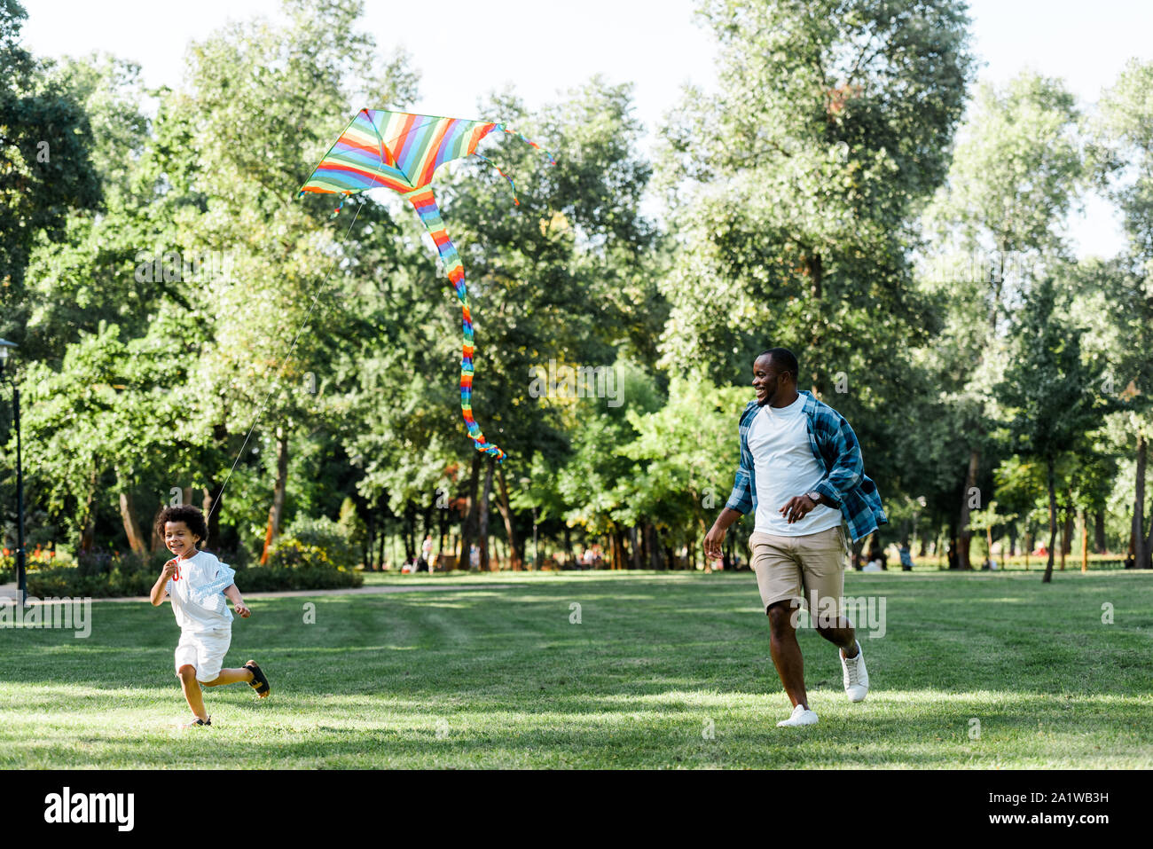 happy african american father and son running near kite in park Stock ...