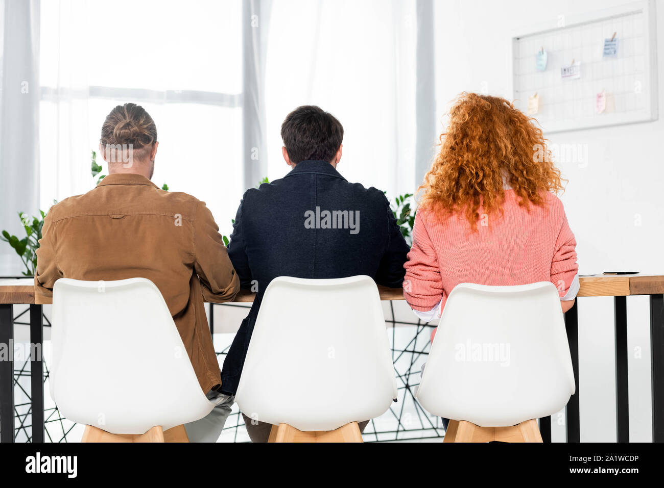 back view of three friends sitting in chairs in office Stock Photo - Alamy