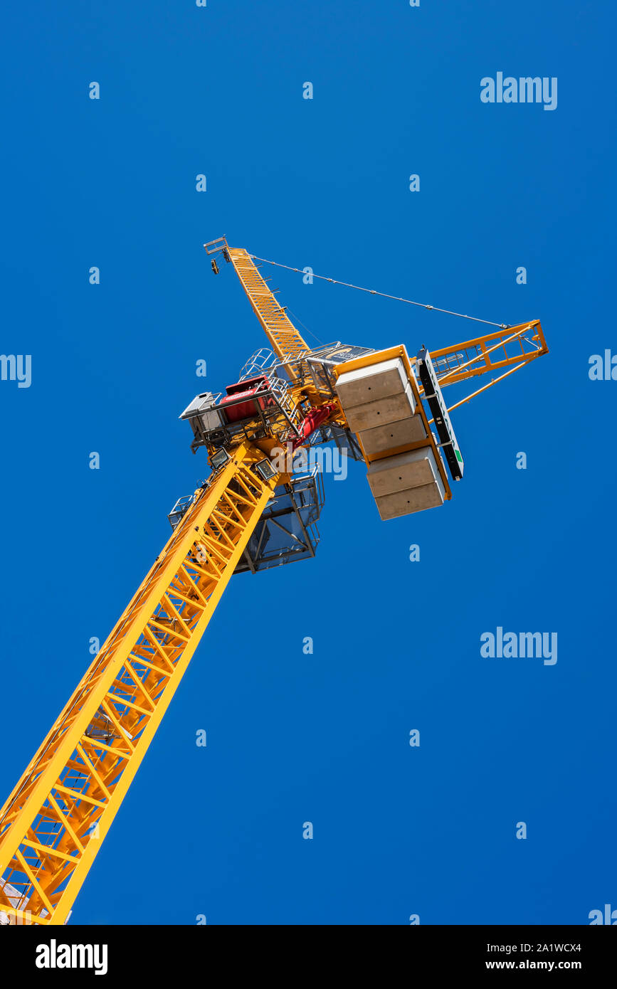 Yellow tower crane contrasting against blue sky background, showing ...